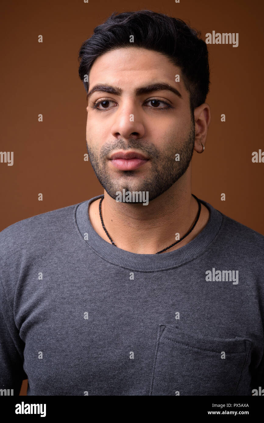 Young handsome Indian man against brown background Stock Photo - Alamy