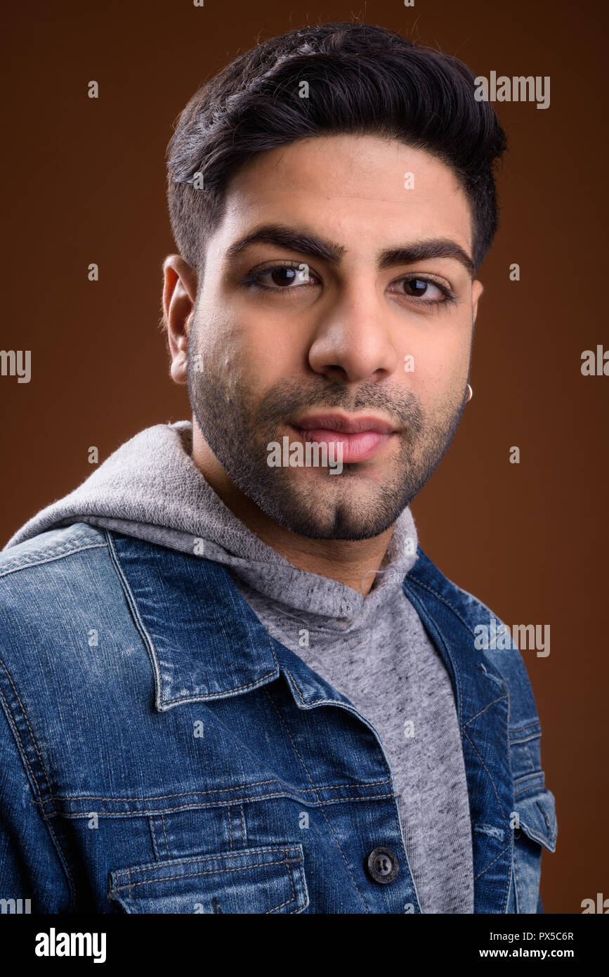 Young handsome Indian man against brown background Stock Photo - Alamy
