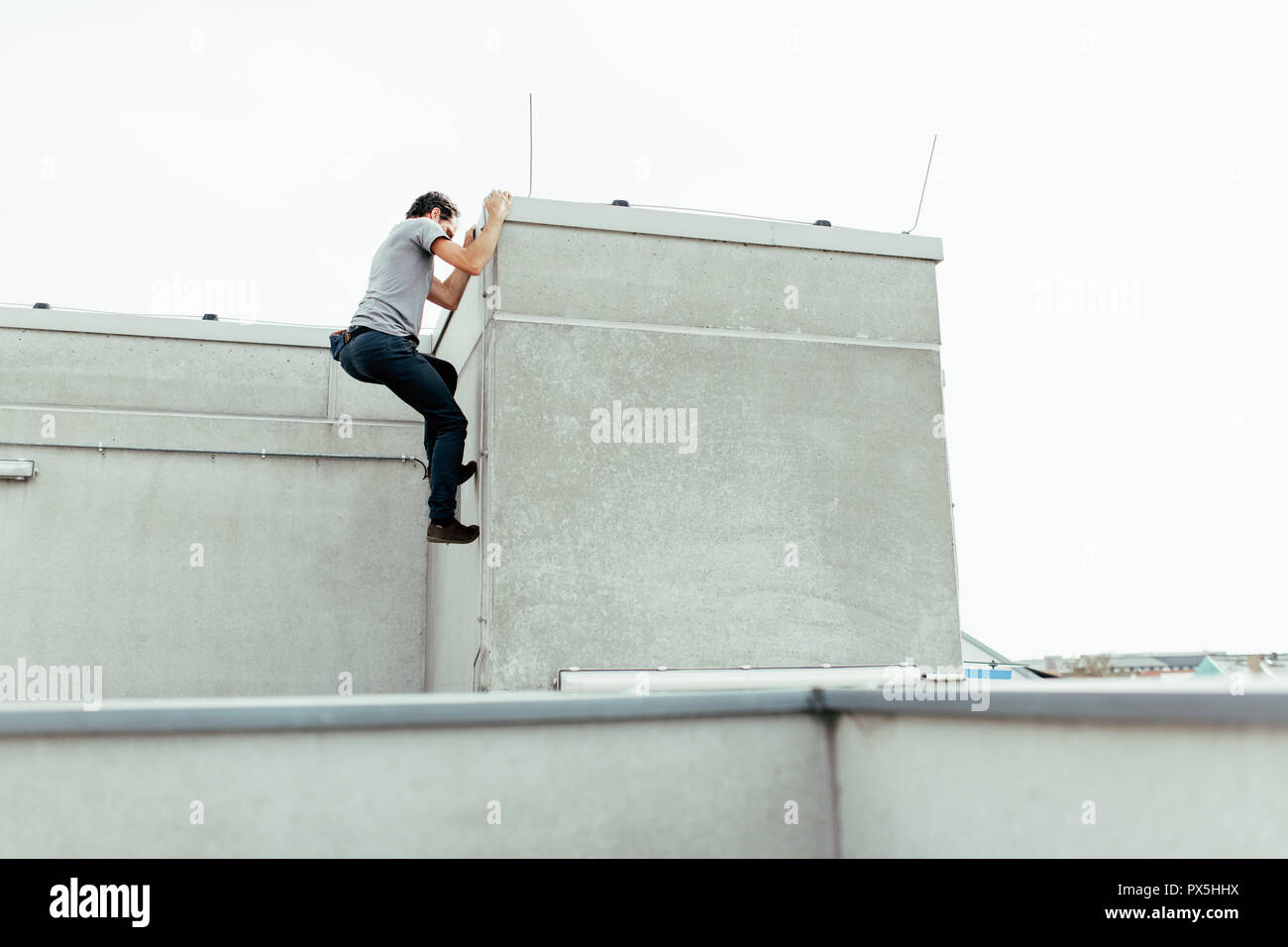 photo of young man climbing the facade of building in the city Stock ...