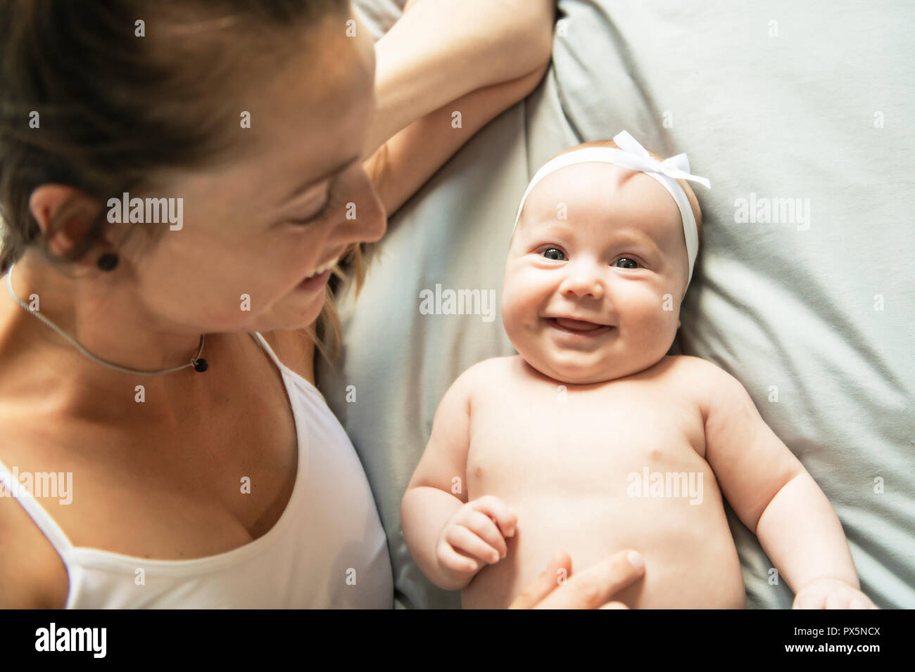 Portrait of a beautiful mother with her 2 month old baby in the bedroom ...