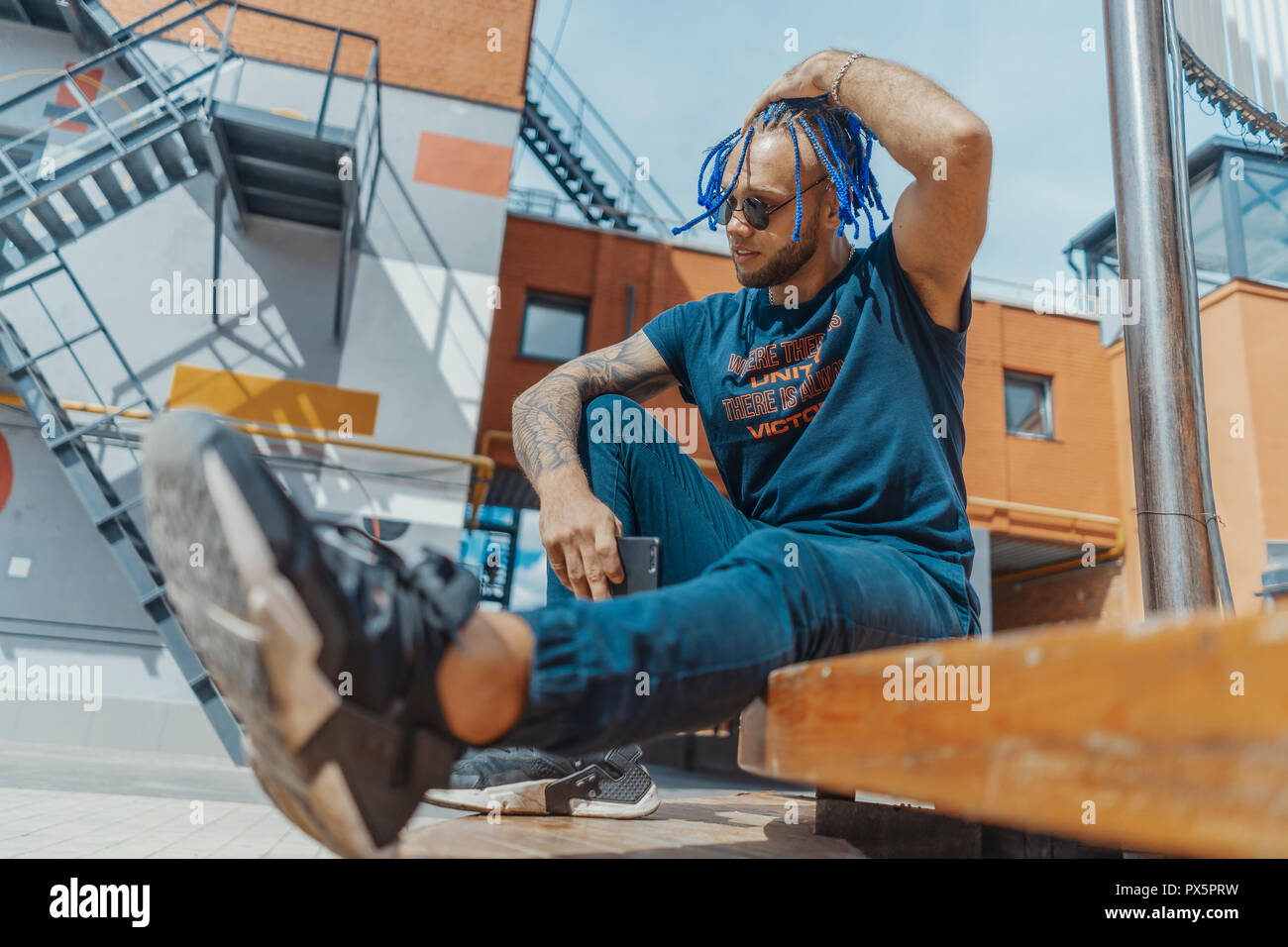 Young attractive man with blue dreadlocks touching his hair Stock Photo ...