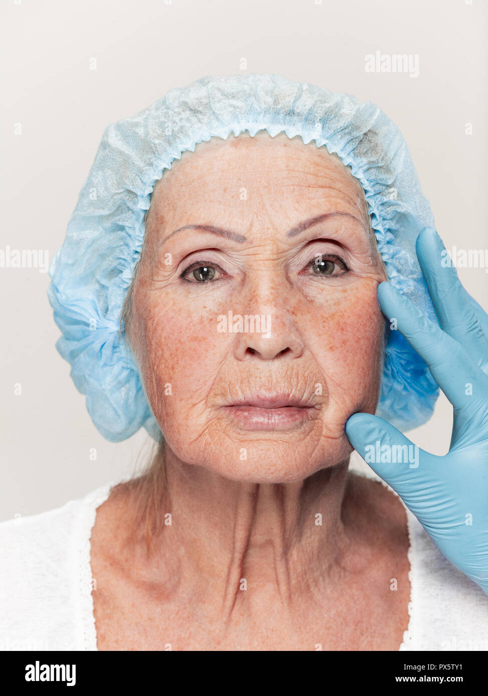 The surgeon doing skin check on mid age woman before plastic surgery ...