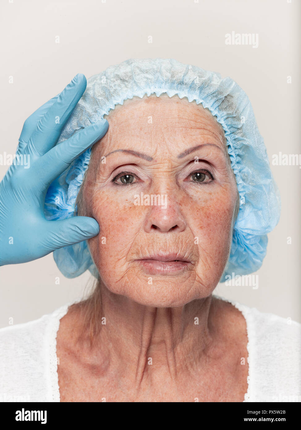 The surgeon doing skin check on mid age woman before plastic surgery ...