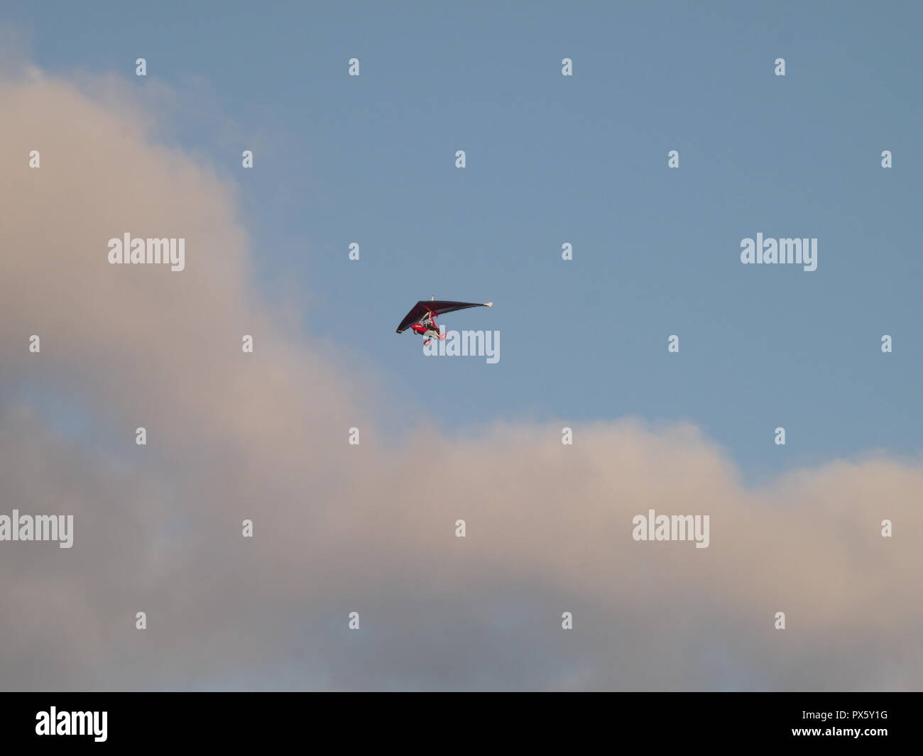 Single micro-light aircraft flying in the sunshine, blue sky and clouds ...