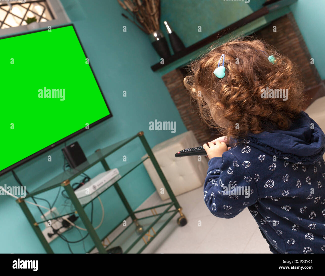 Toddler girl watching television with a remote control Stock Photo - Alamy