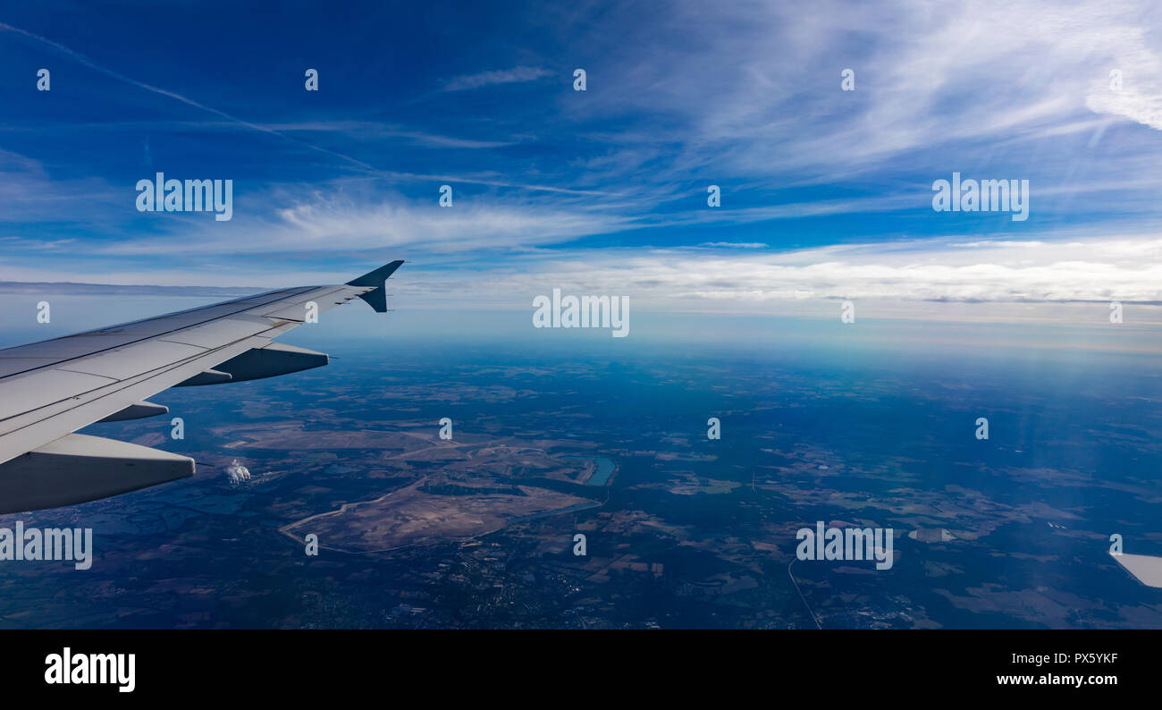 Aerial view out of a plane window. Cloudy blue sky over countryside ...