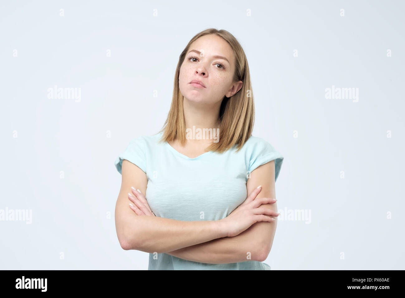 Portrait of beautiful young woman with arms crossed is standing with ...