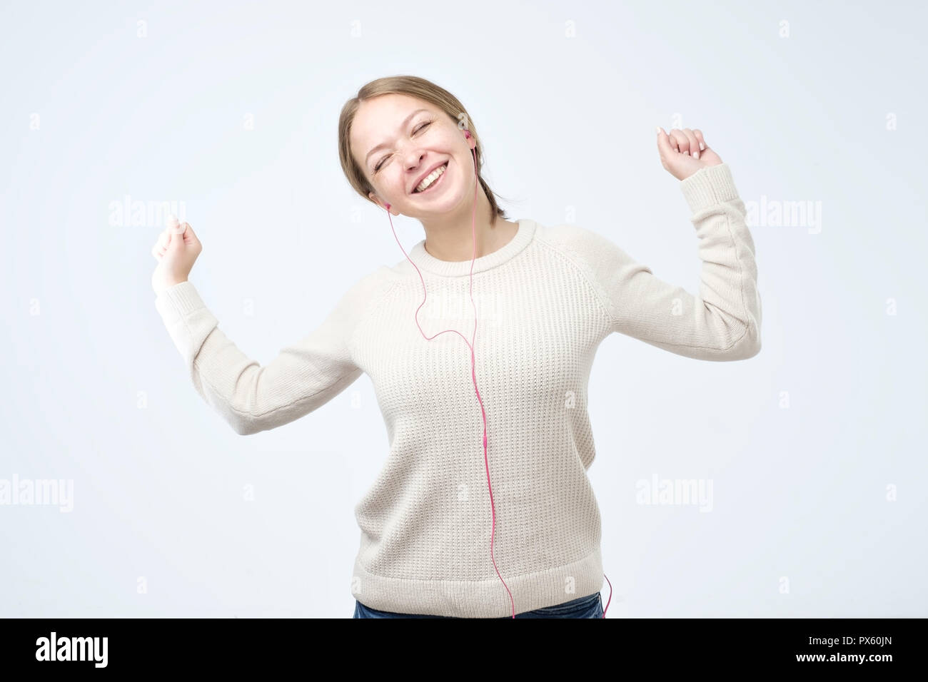 Beautiful young woman in headphones listening to music on light ...