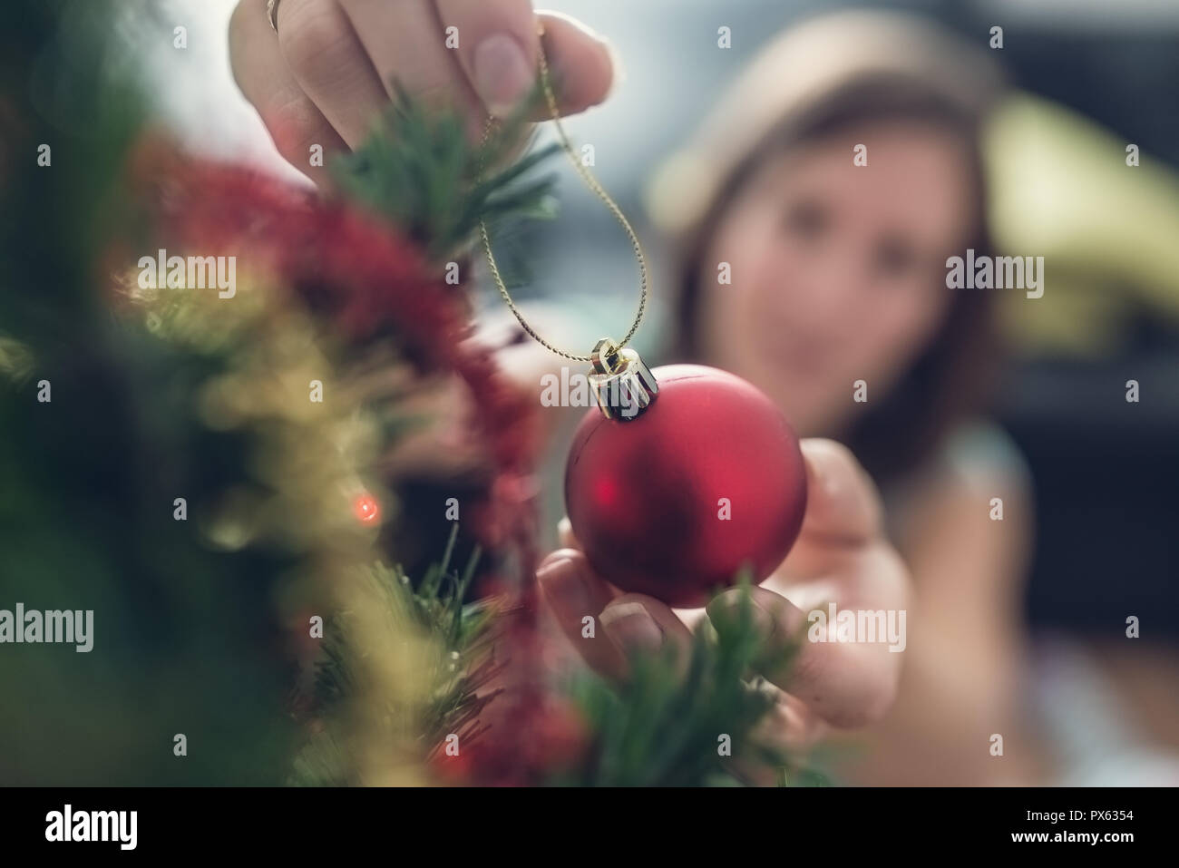 Retro vintage image of a young woman hanging red holiday bauble on ...