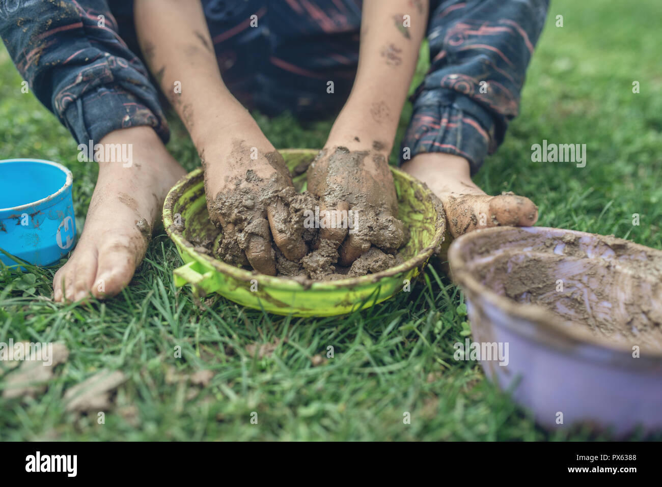 Retro image of toddler child sitting in grass playing with mud having ...