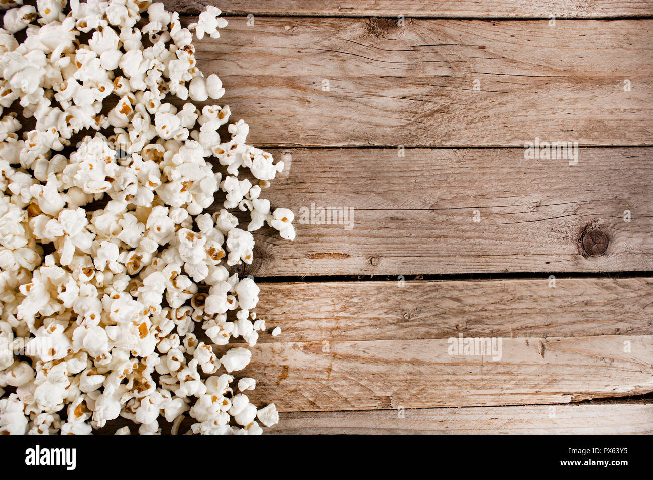 Spilled popcorn on wooden and retro desk and space for design and text ...