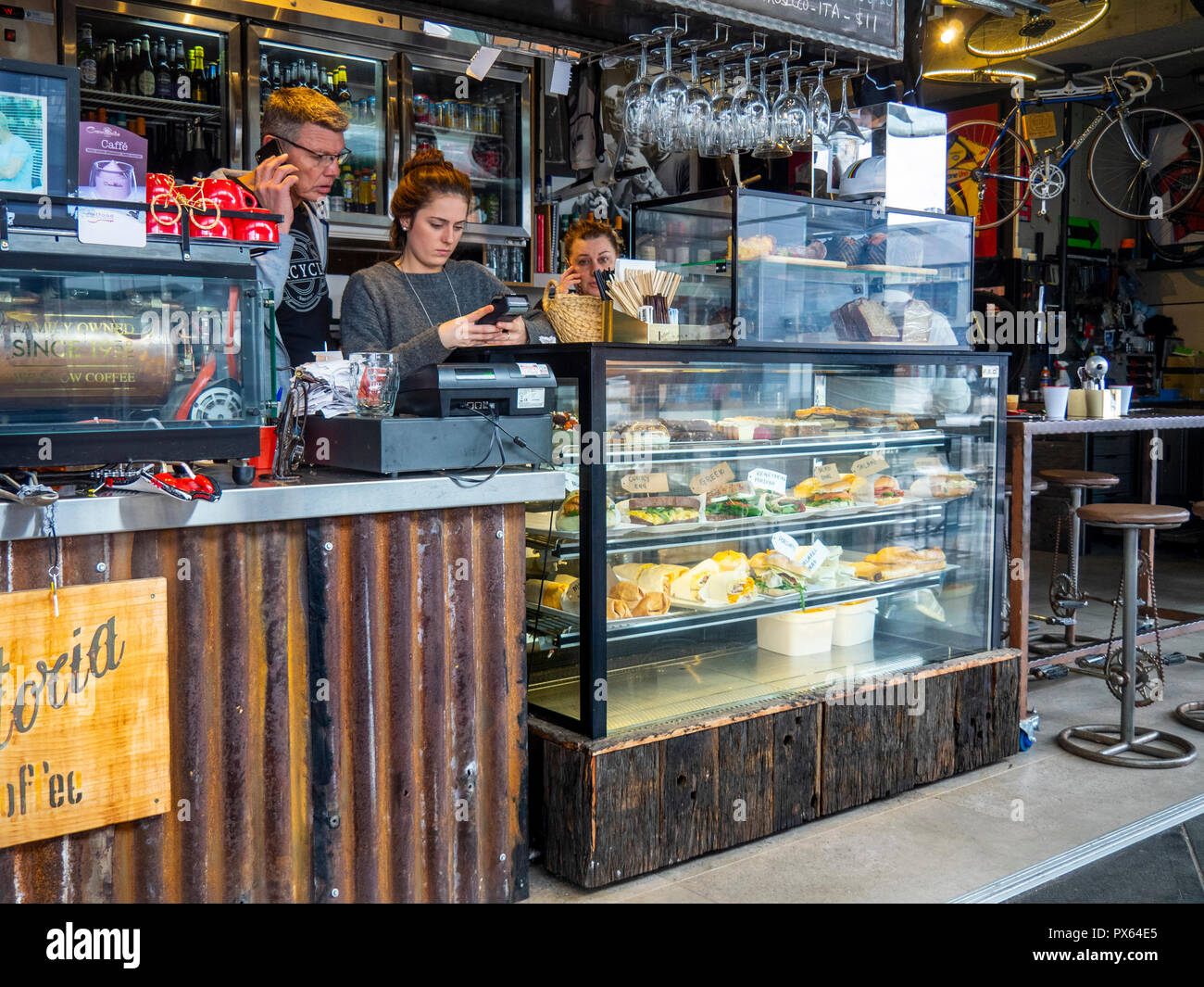 male and two females standing behind the counter of a coffee shop ...