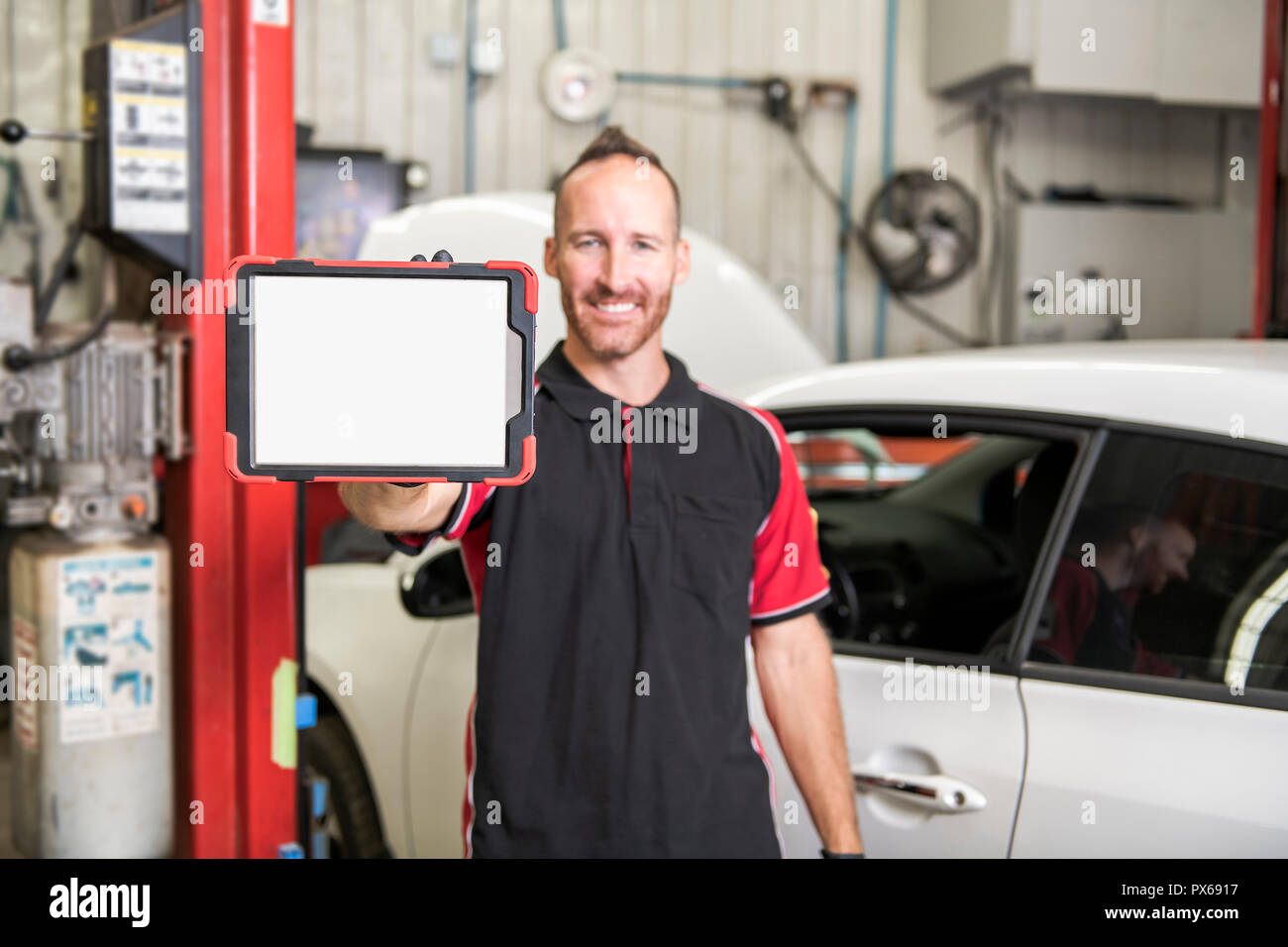 A Portrait of handsome mechanic based on car in auto repair shop Stock ...
