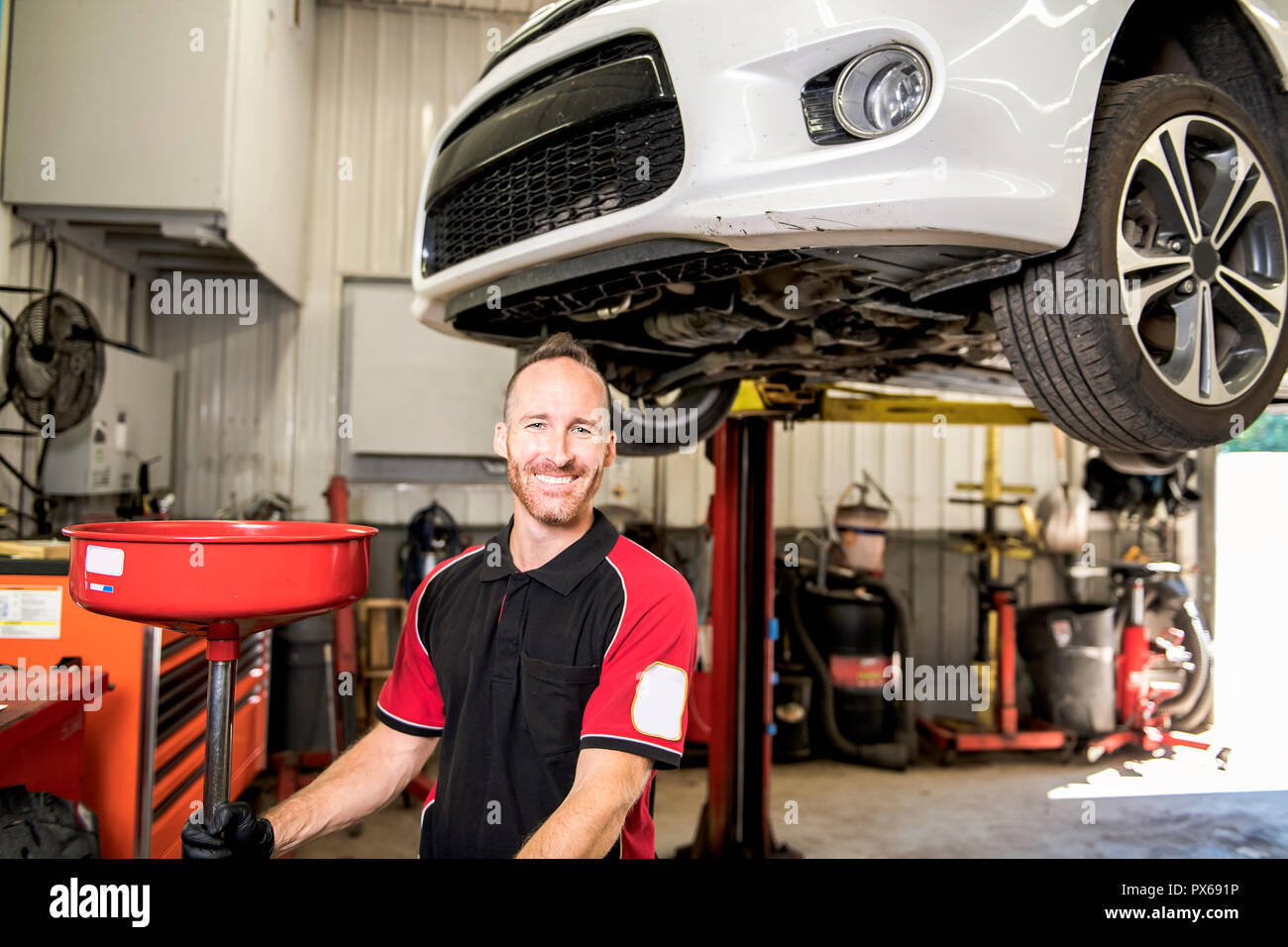A Portrait of handsome mechanic based on car in auto repair shop Stock ...