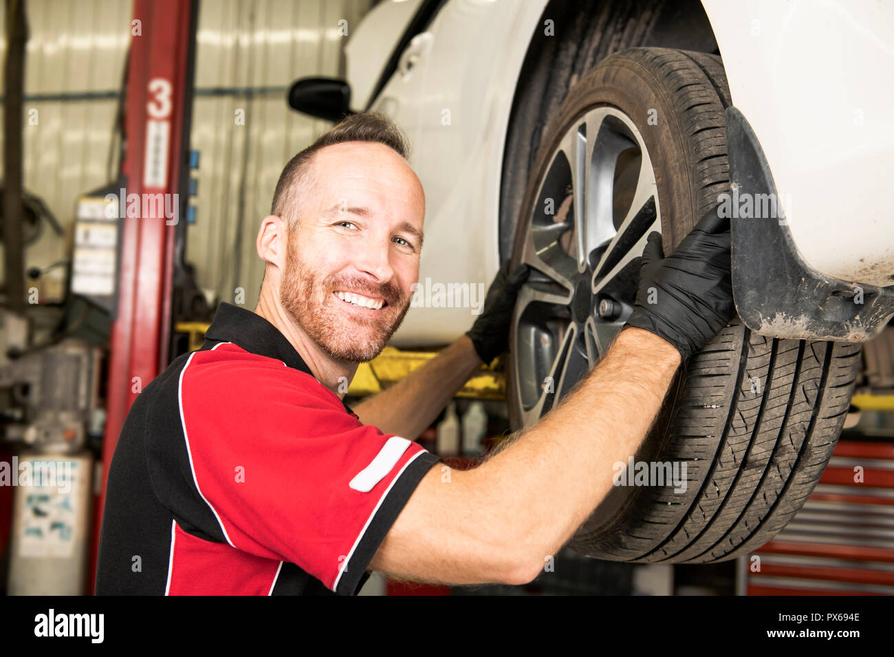 A Portrait of handsome mechanic based on car in auto repair shop Stock ...