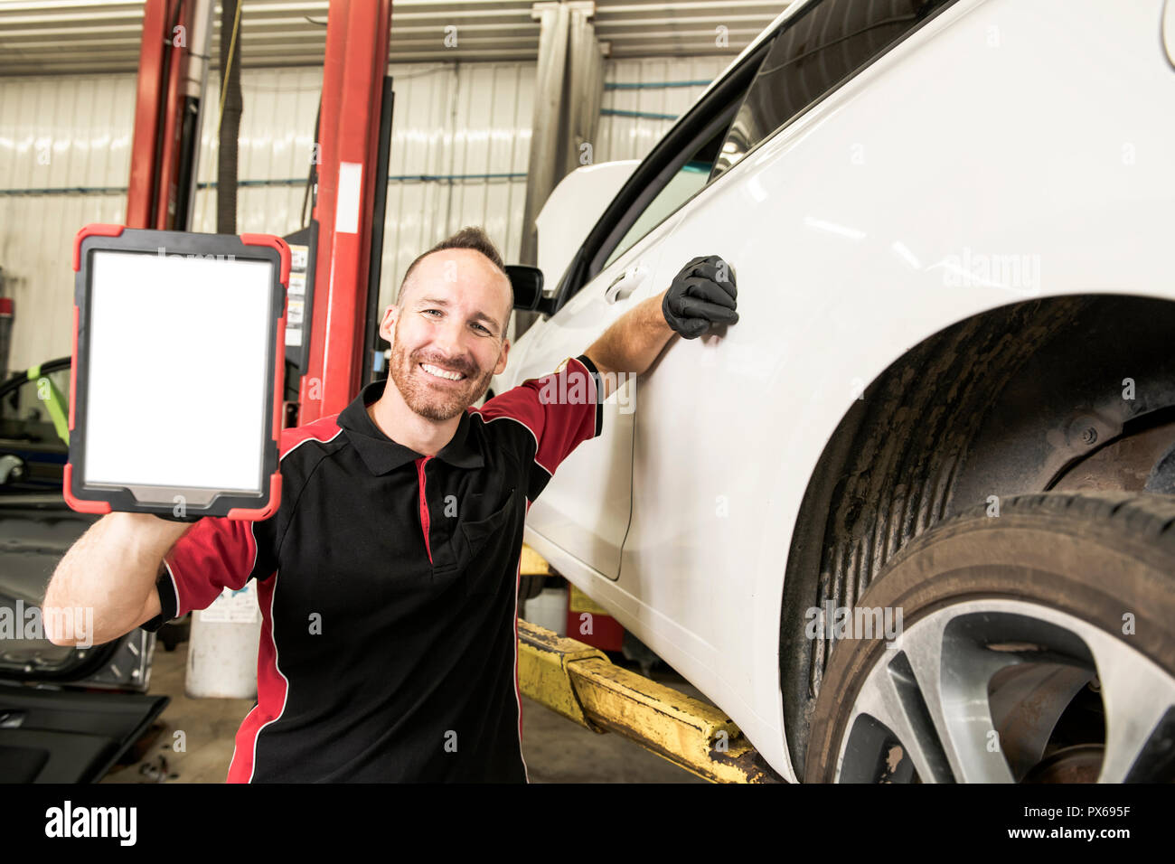 A Portrait of handsome mechanic based on car in auto repair shop Stock ...