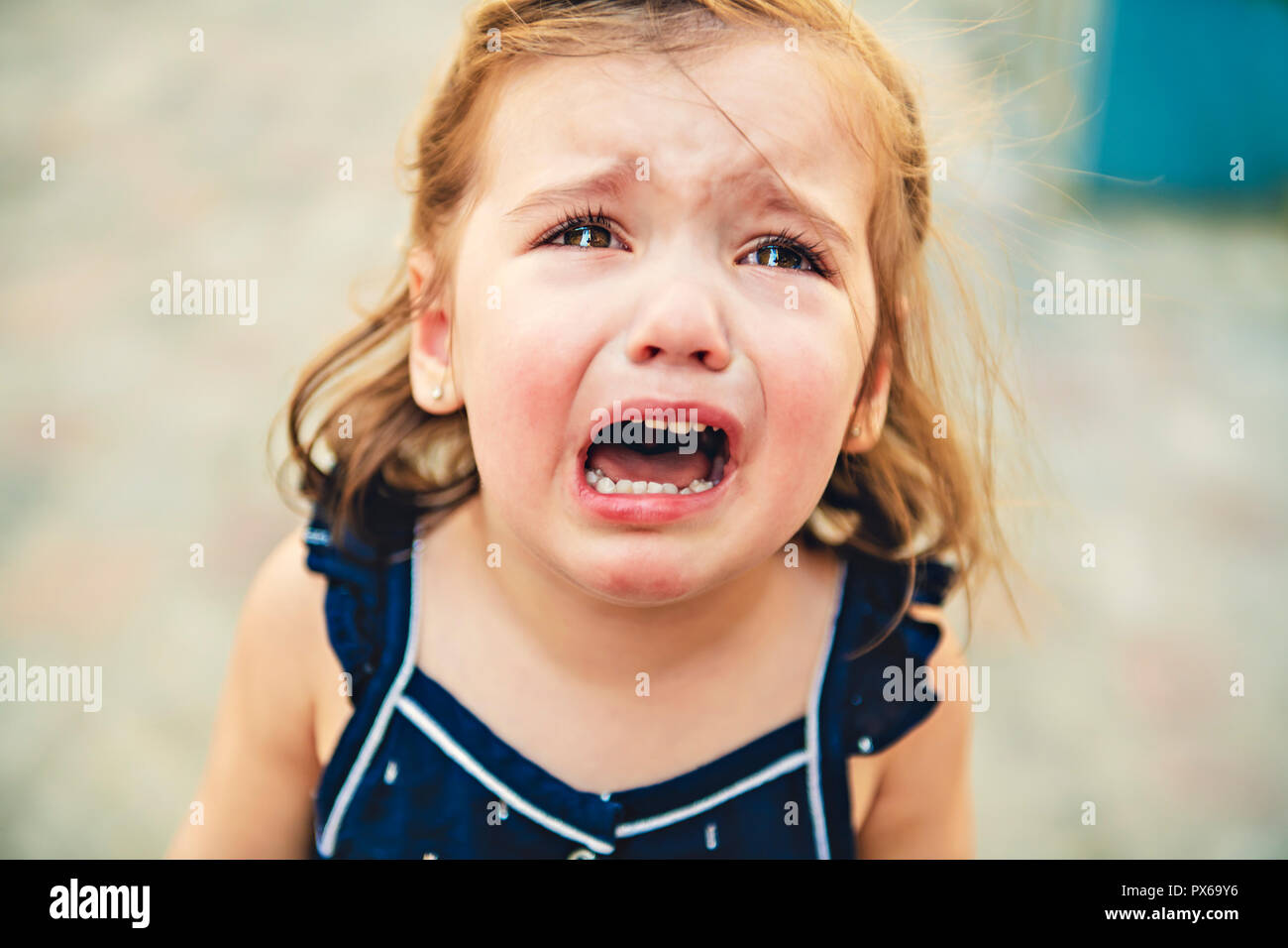 Close up portrait of crying little toddler girl with outdoors ...