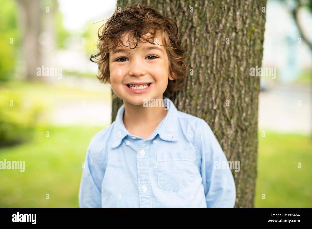 A Cute Caucasian boy happily close to a tree Stock Photo - Alamy