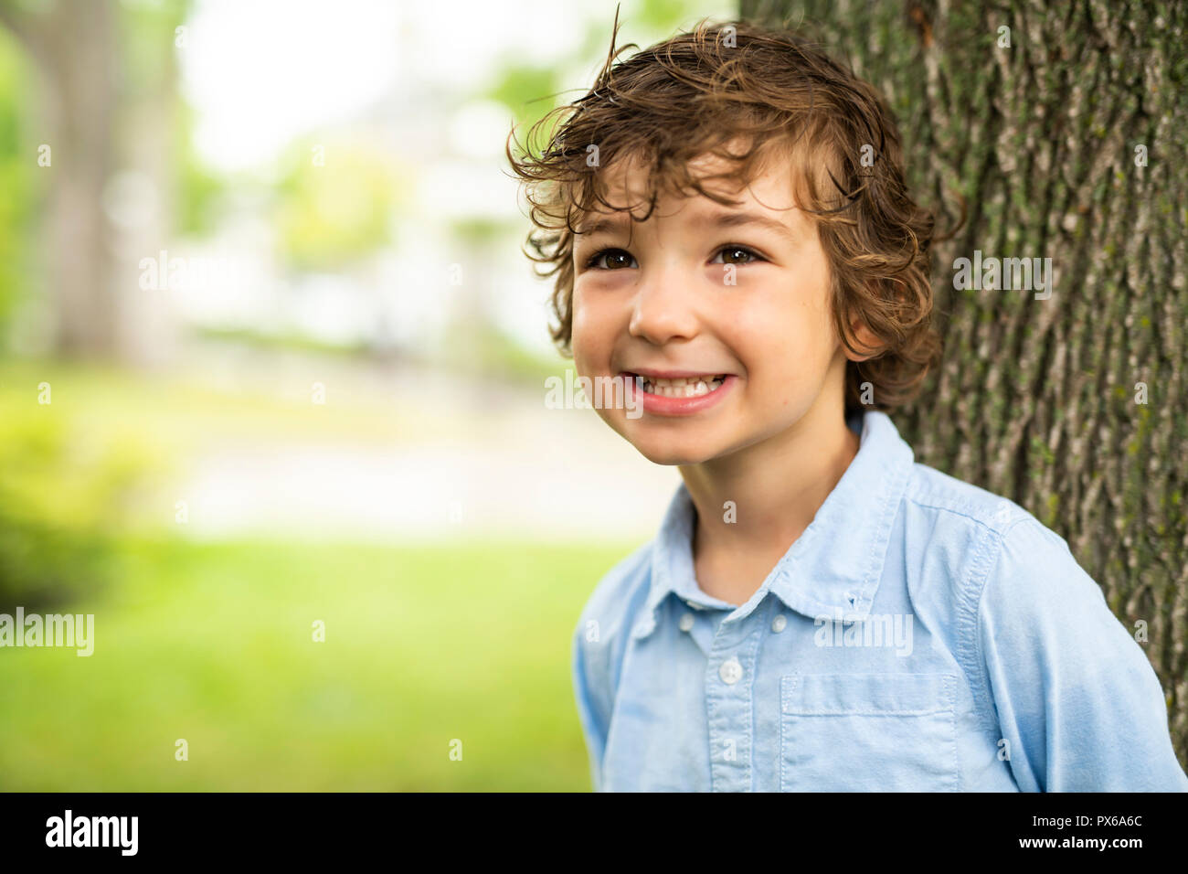 A Cute Caucasian boy happily close to a tree Stock Photo - Alamy