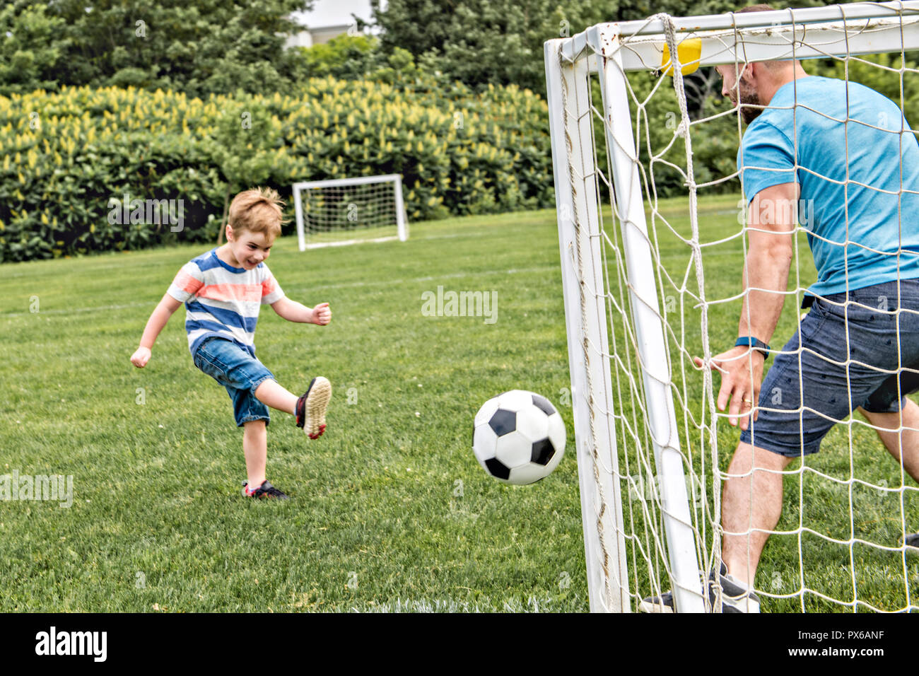 A man with child playing football outside on field Stock Photo - Alamy