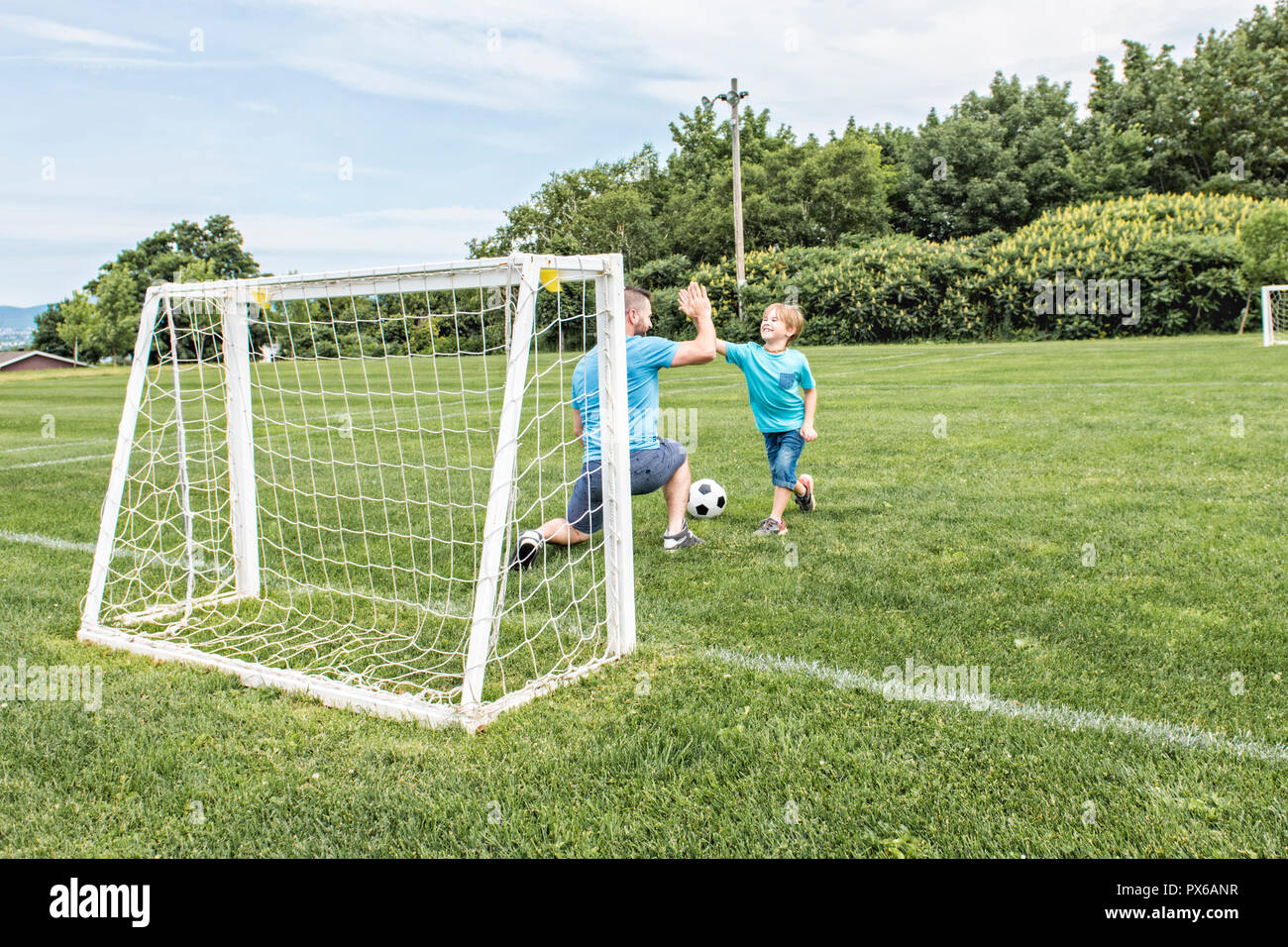 A man with child playing football outside on field Stock Photo - Alamy