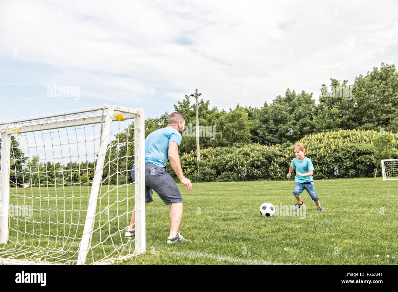 A man with child playing football outside on field Stock Photo - Alamy