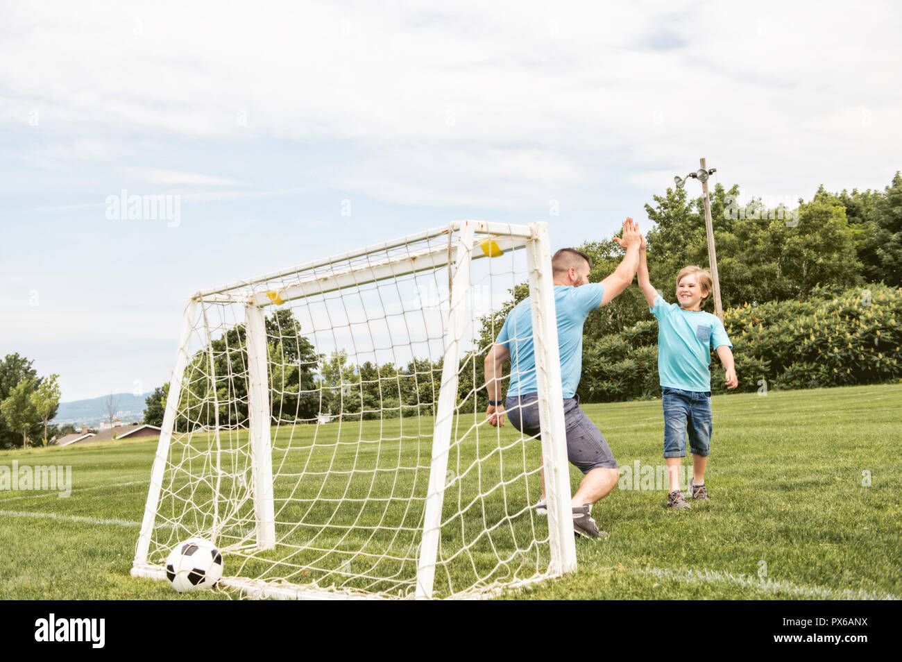 A man with child playing football outside on field Stock Photo - Alamy
