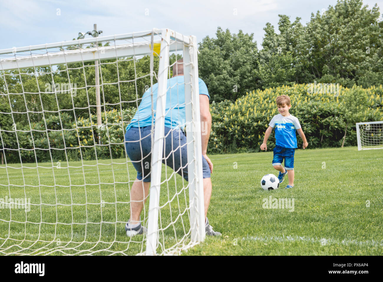 A man with child playing football outside on field Stock Photo - Alamy