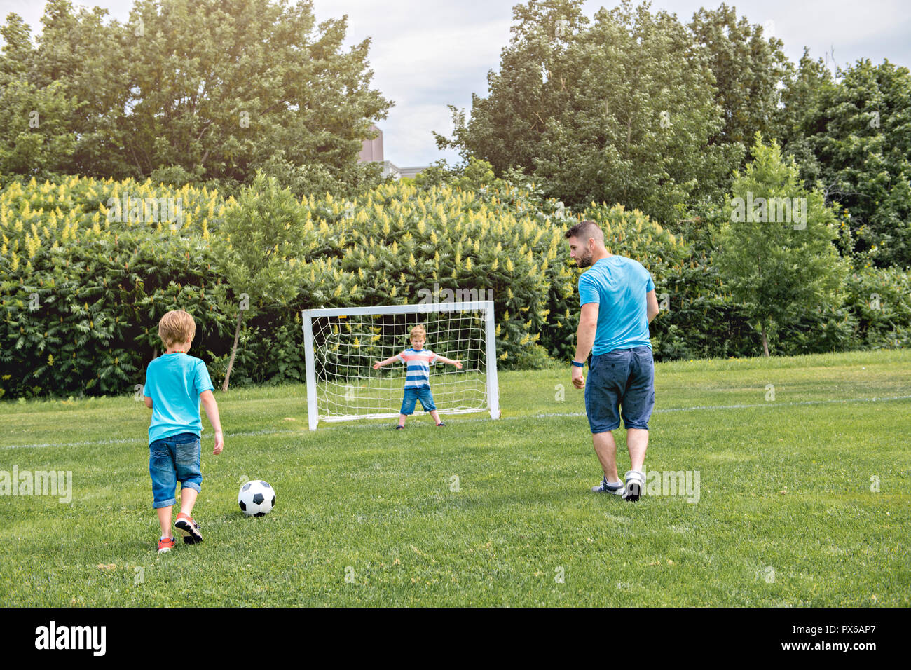 A man with child playing football outside on field Stock Photo - Alamy