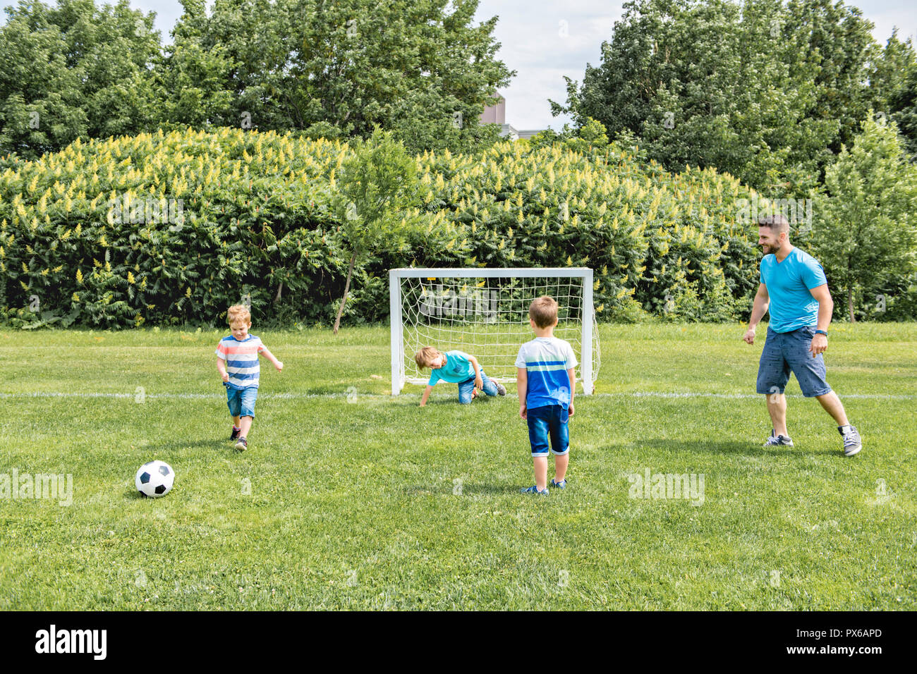 A man with child playing football outside on field Stock Photo - Alamy