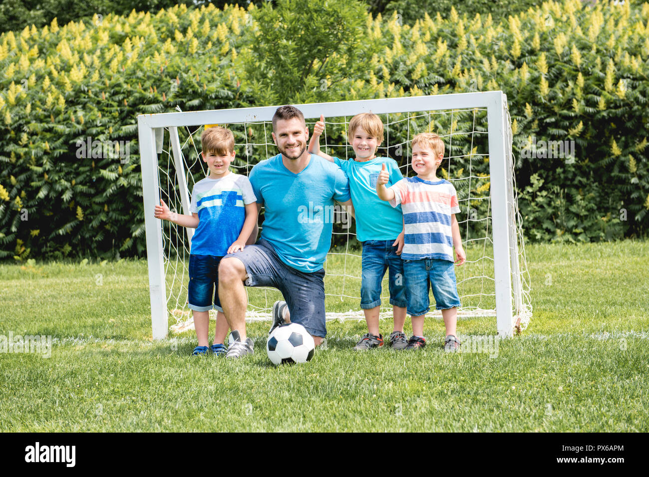 A man with child playing football outside on field Stock Photo - Alamy