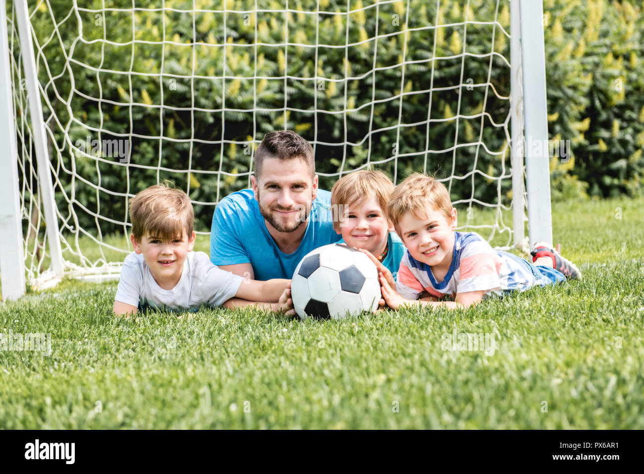 A man with child playing football outside on field Stock Photo - Alamy