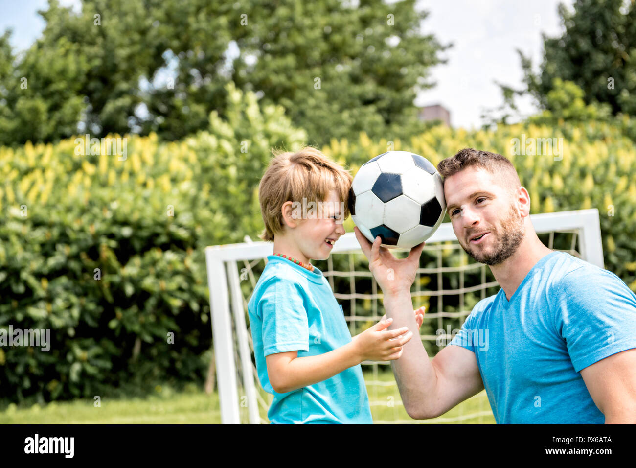 A man with child playing football outside on field Stock Photo - Alamy