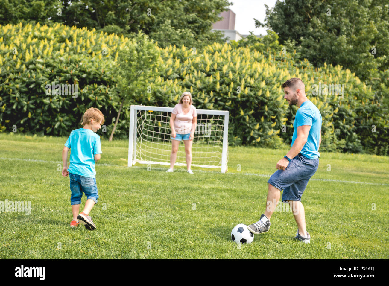 A man with child playing football outside on field Stock Photo - Alamy