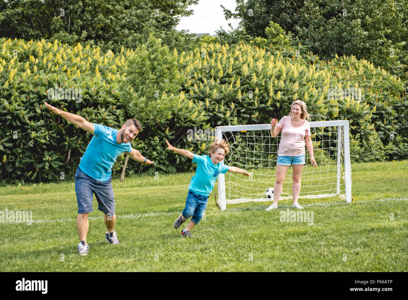 A man with child playing football outside on field Stock Photo - Alamy