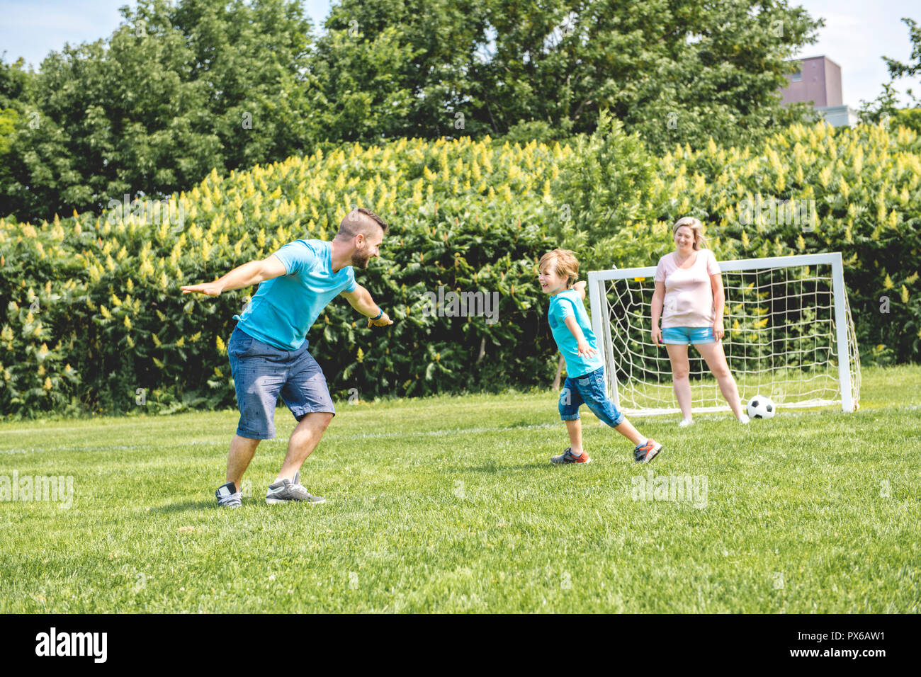 A man with child playing football outside on field Stock Photo - Alamy