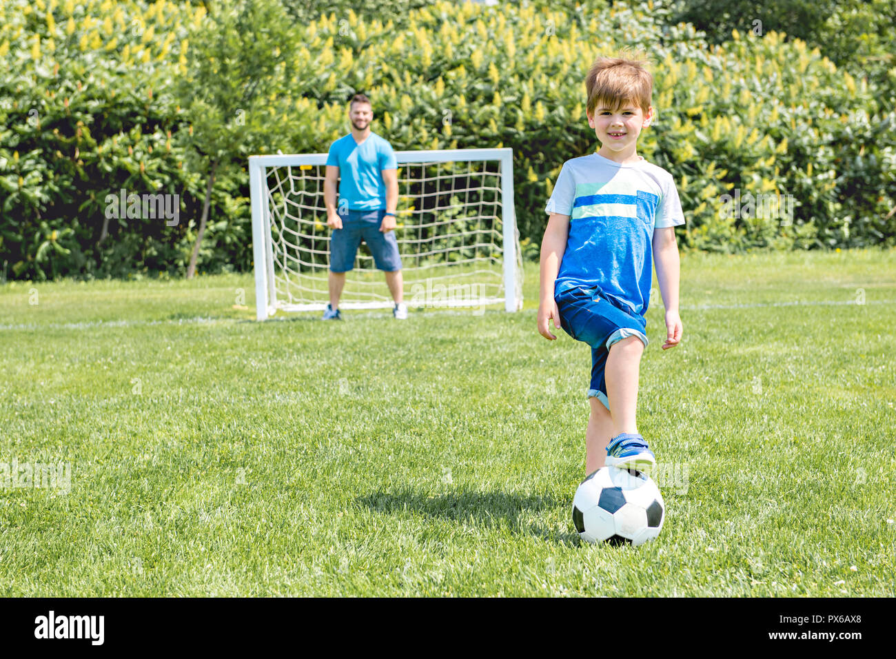 A man with child playing football outside on field Stock Photo - Alamy