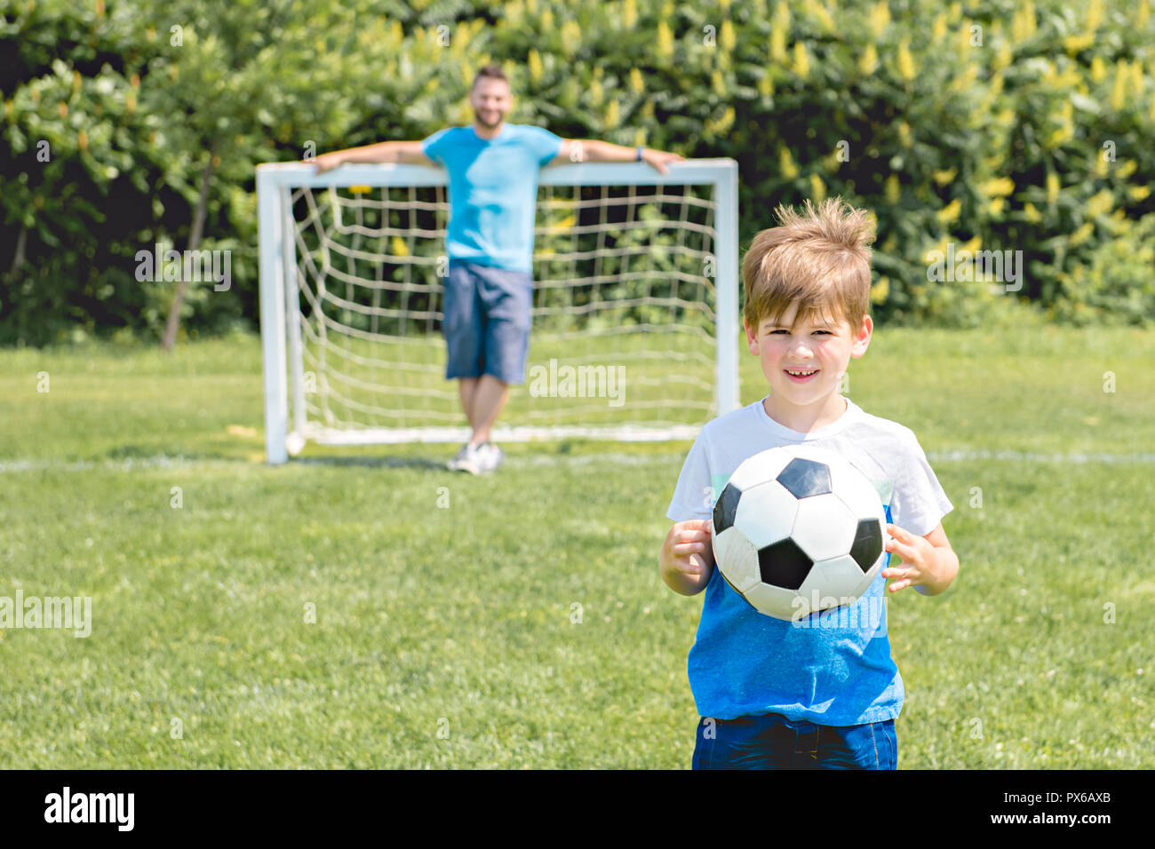 A man with child playing football outside on field Stock Photo - Alamy
