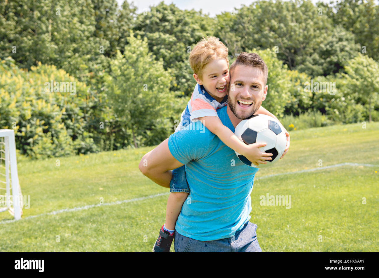 A man with child playing football outside on field Stock Photo - Alamy