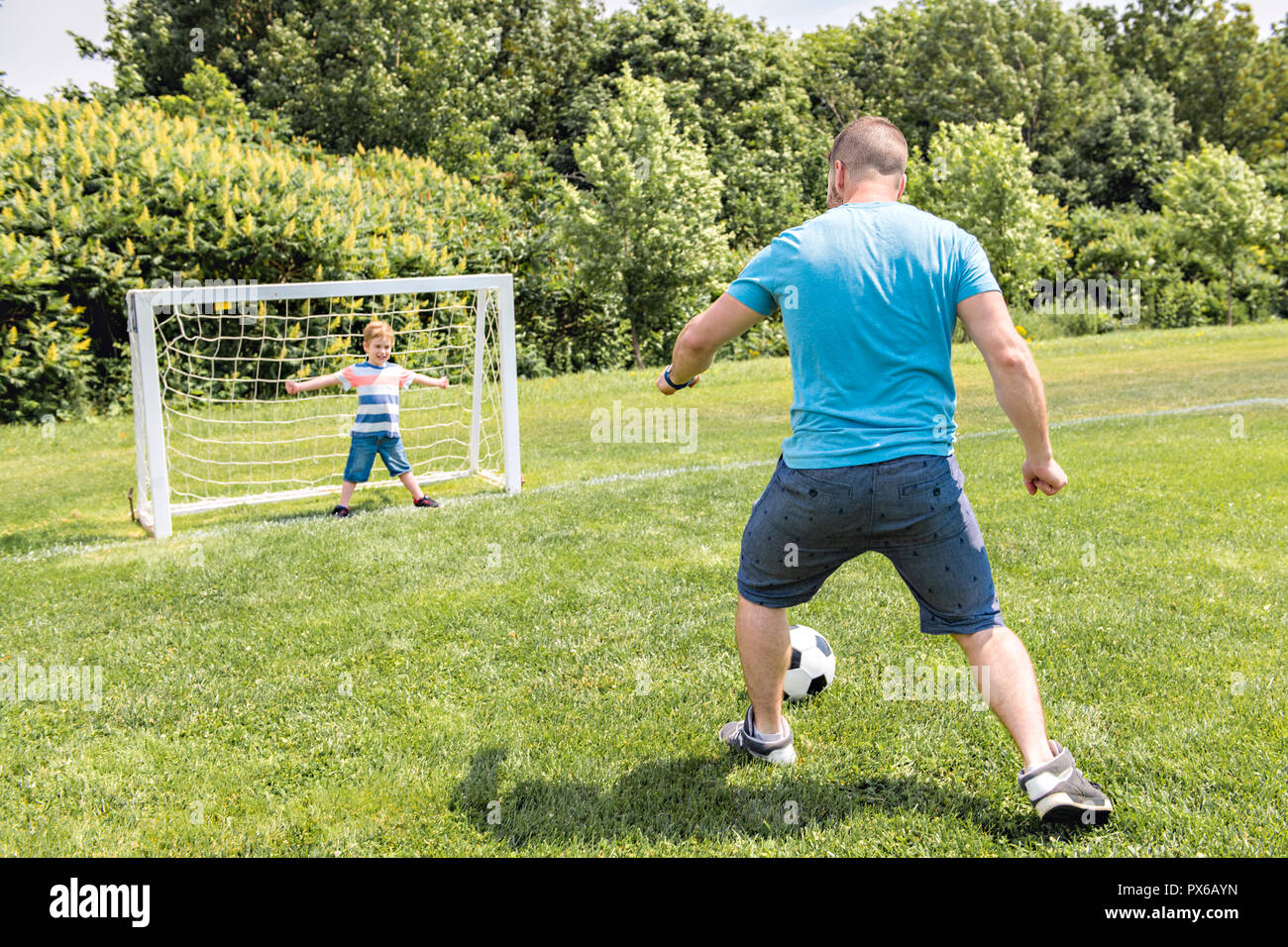A man with child playing football outside on field Stock Photo - Alamy