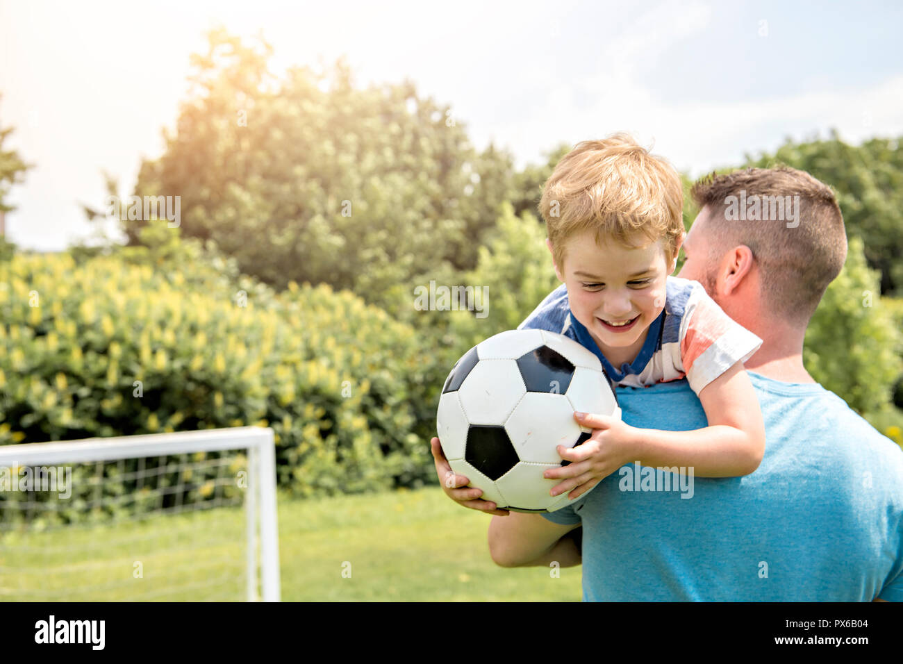 A man with child playing football outside on field Stock Photo - Alamy