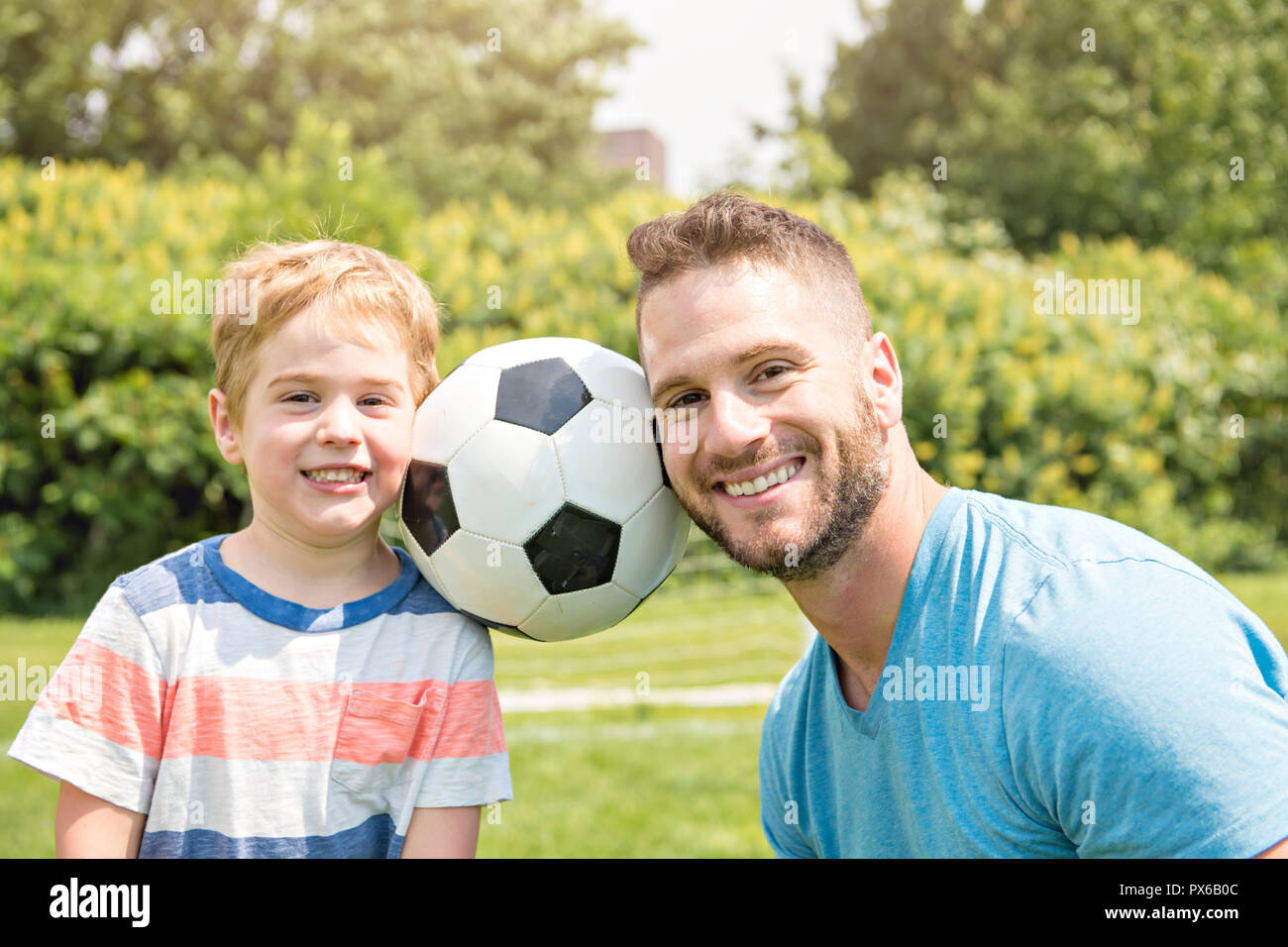 A man with child playing football outside on field Stock Photo - Alamy
