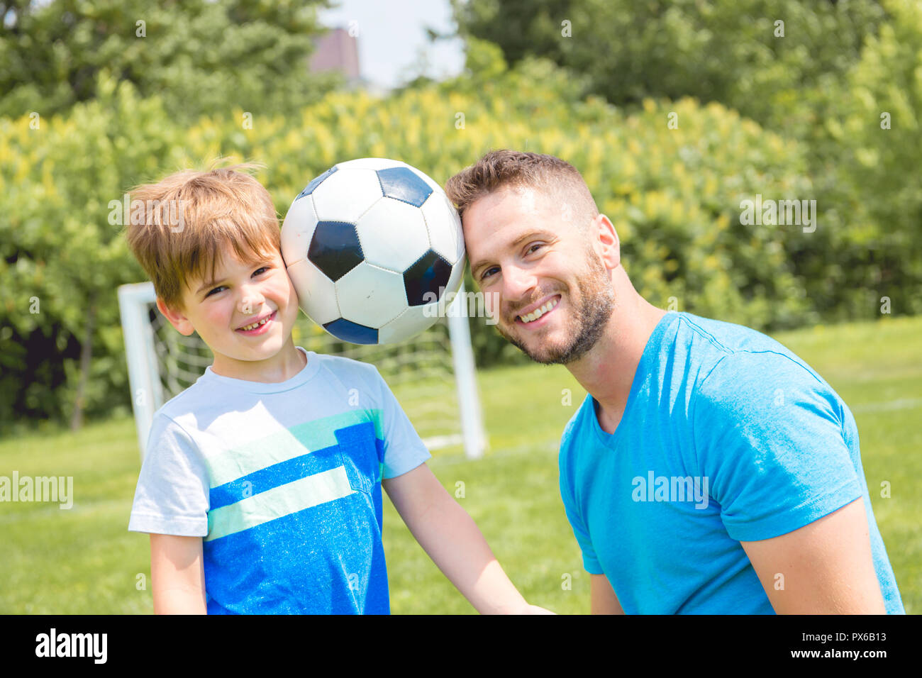 A man with child playing football outside on field Stock Photo - Alamy