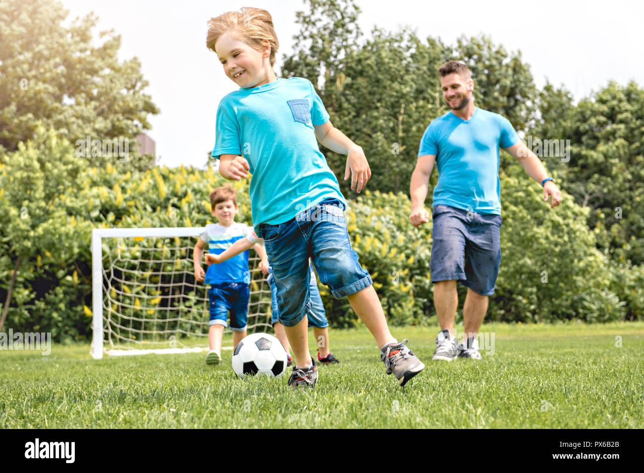A man with child playing football outside on field Stock Photo - Alamy