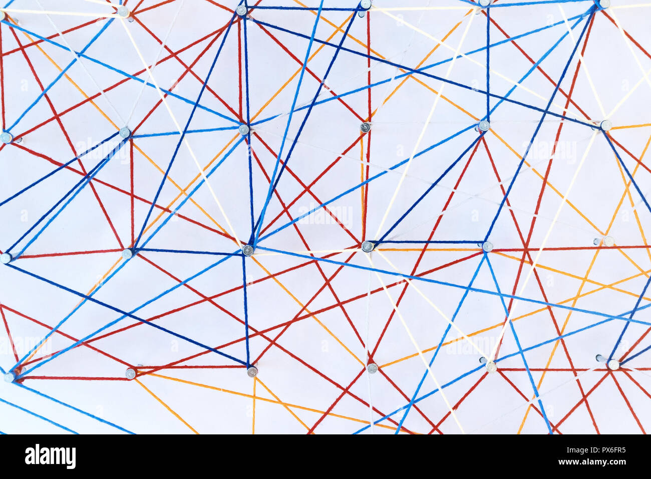 Abstract colored threads are stretched on pins on white background ...