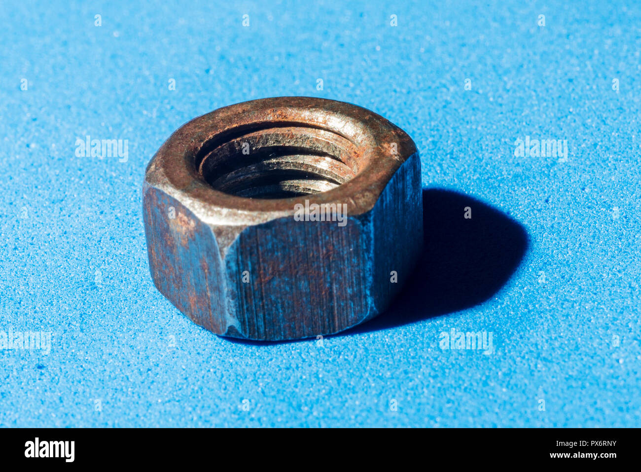 old rusty nut isolated on light blue background Stock Photo - Alamy