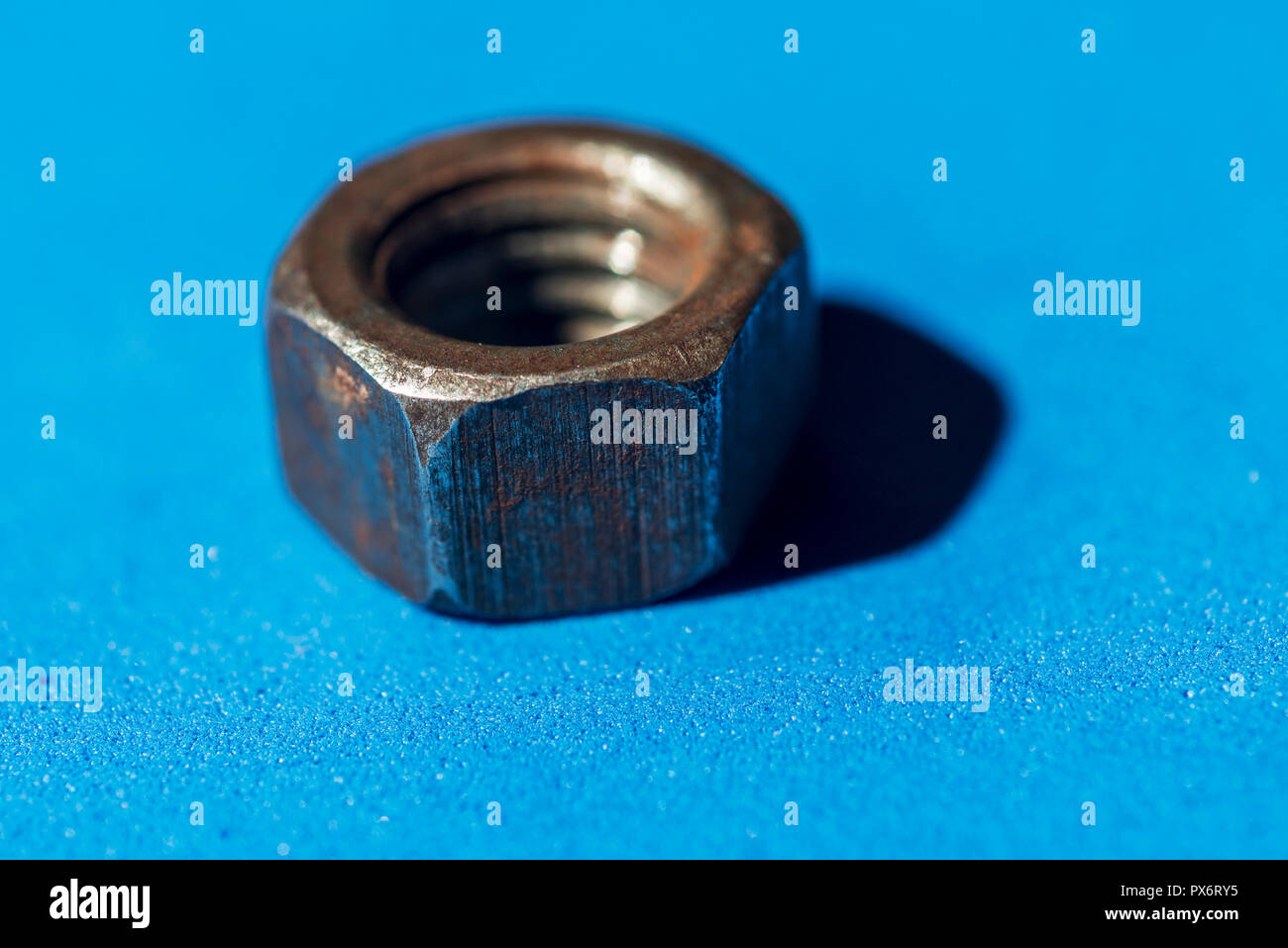 old rusty nut isolated on light blue background Stock Photo - Alamy