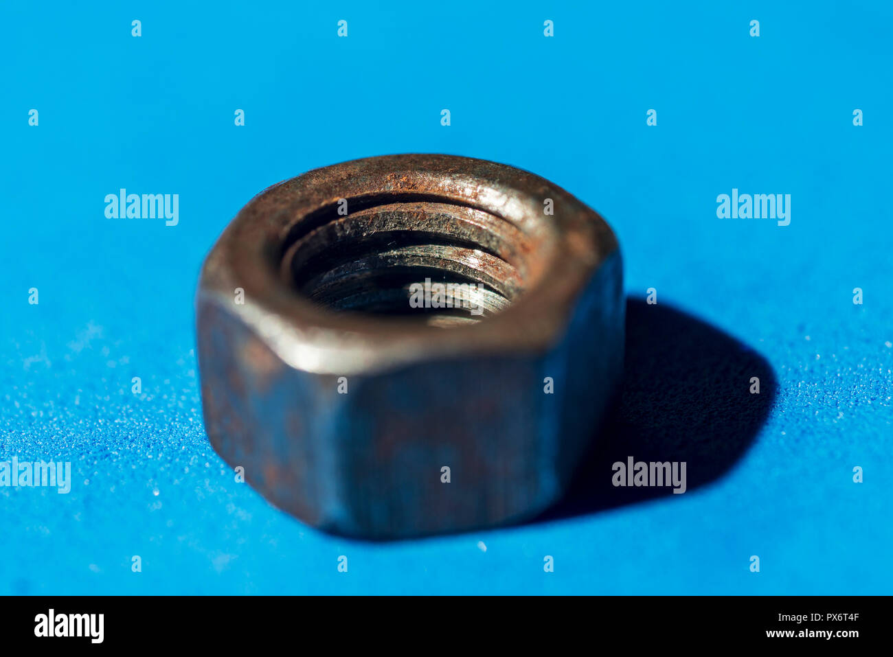 old rusty nut isolated on light blue background Stock Photo - Alamy