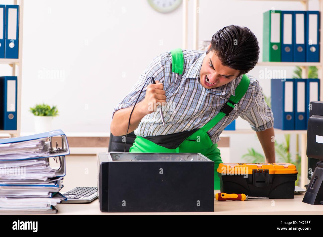 Young engineer repairing broken computer at the office Stock Photo - Alamy