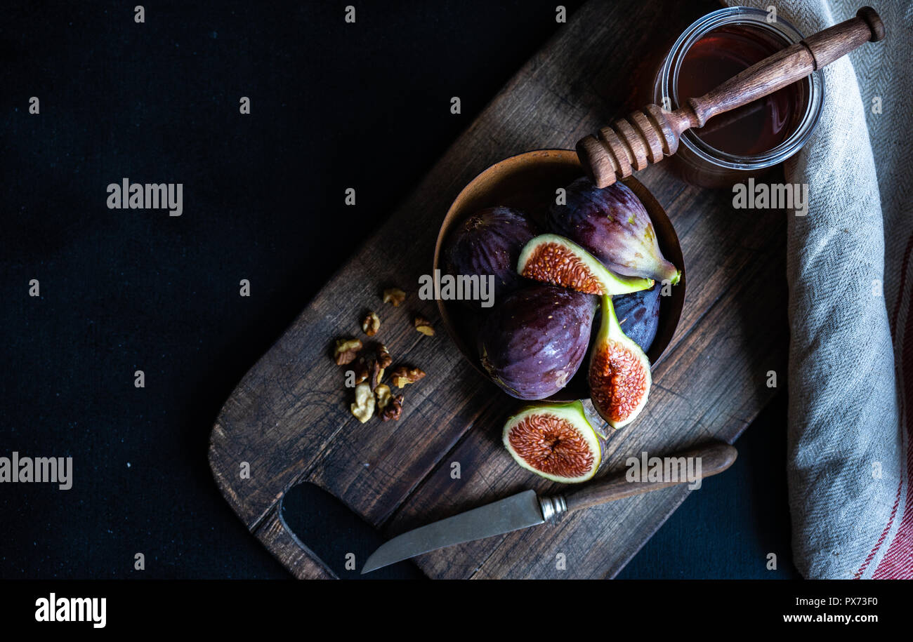 Autumnal ripe fig fruits in woode bowl with honey and huts as a ...
